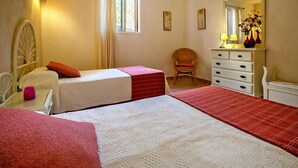 Quarto com duas camas, uma cadeira, cômoda e espelho.