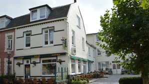 Um edifício de estilo europeu tradicional com um café chamado 'Leeuw Bier' no andar térreo.