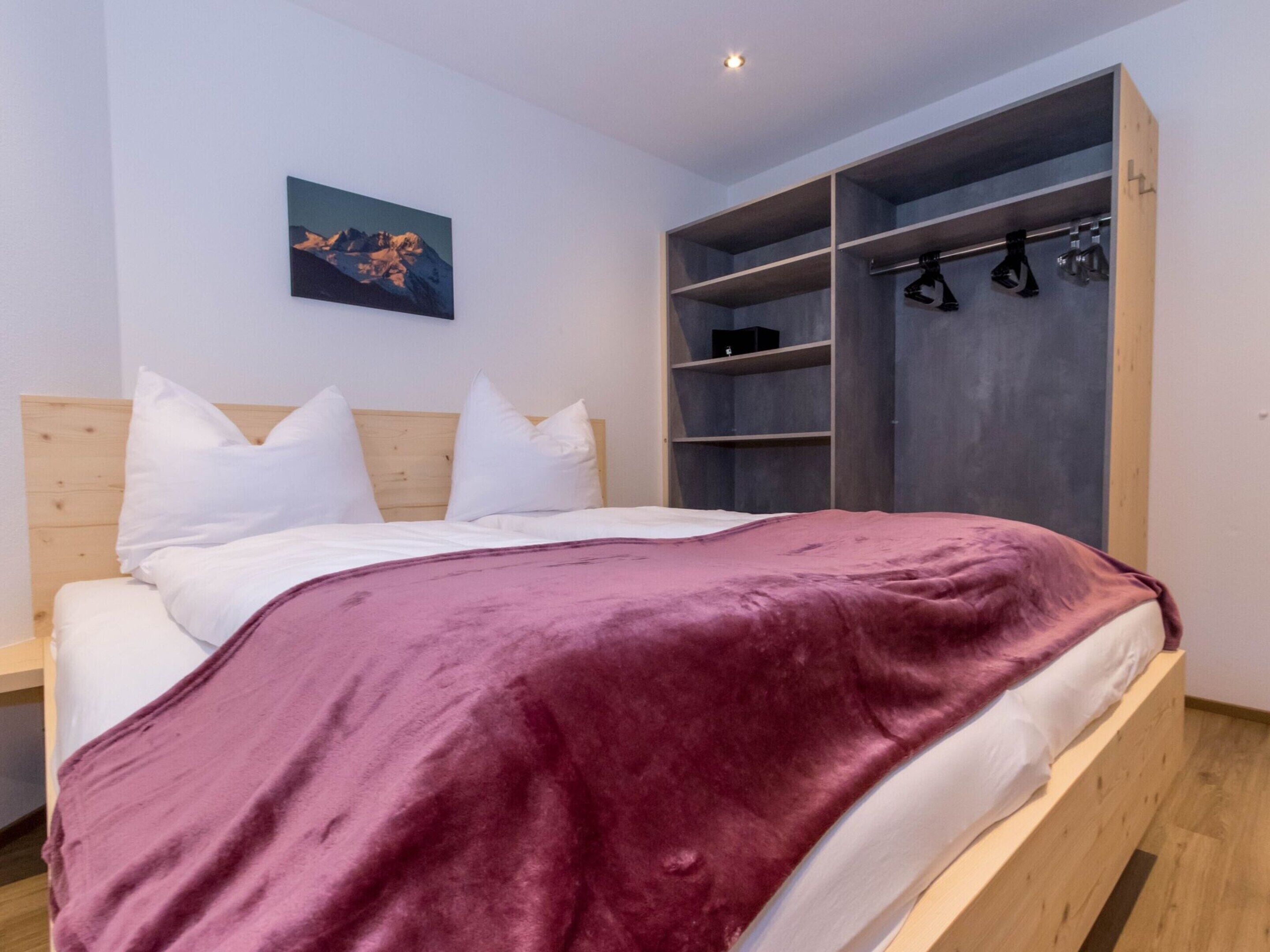 Quarto com cama, guarda-roupa e um quadro na parede.