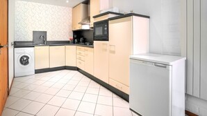 Cozinha compacta com máquina de lavar roupa, micro-ondas e máquina de lavar louça.