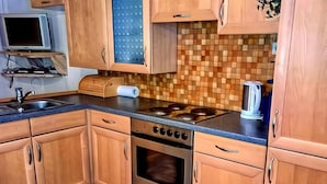 Cozinha com armários de madeira, fogão e painel de azulejos.