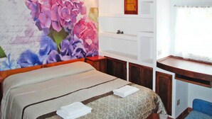 Quarto com uma cama, uma escrivaninha e um grande mural floral na parede.