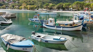 Uma marina com vários barcos atracados, cercada por uma paisagem montanhosa e alguns edifícios ao fundo.