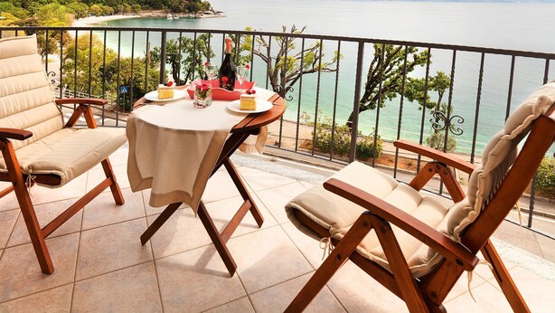 Terraço com mesa posta para dois, com vista para a costa.