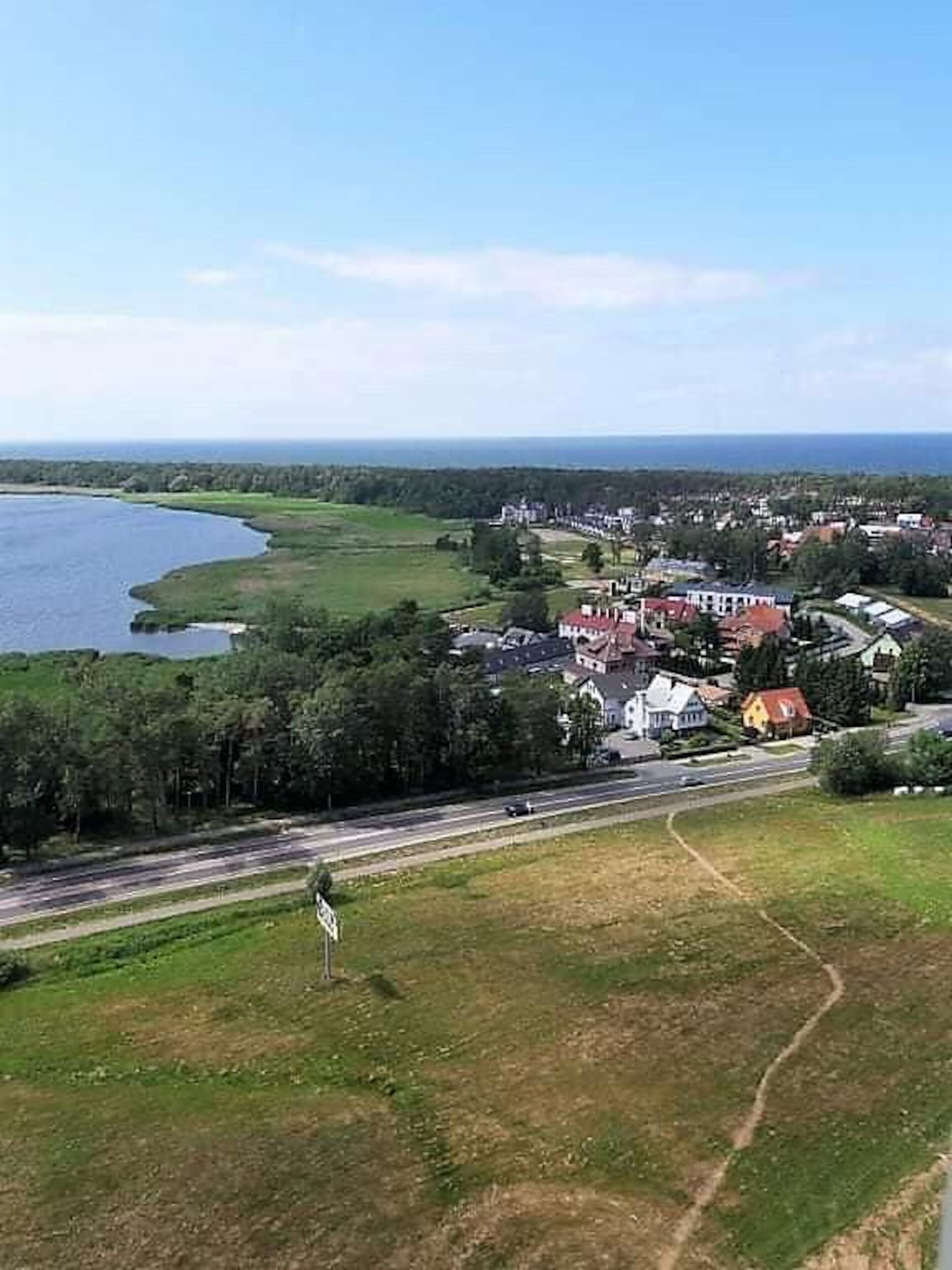 Uma vila costeira com uma estrada principal, uma grande massa de água e um conjunto de edifícios com telhados vermelhos.