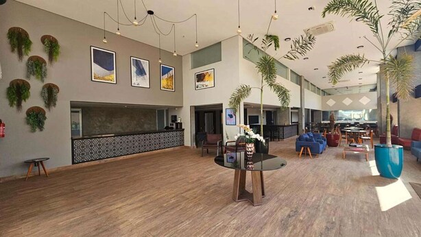 Um hall amplo com balcão de recepção, área de estar e plantas decorativas.