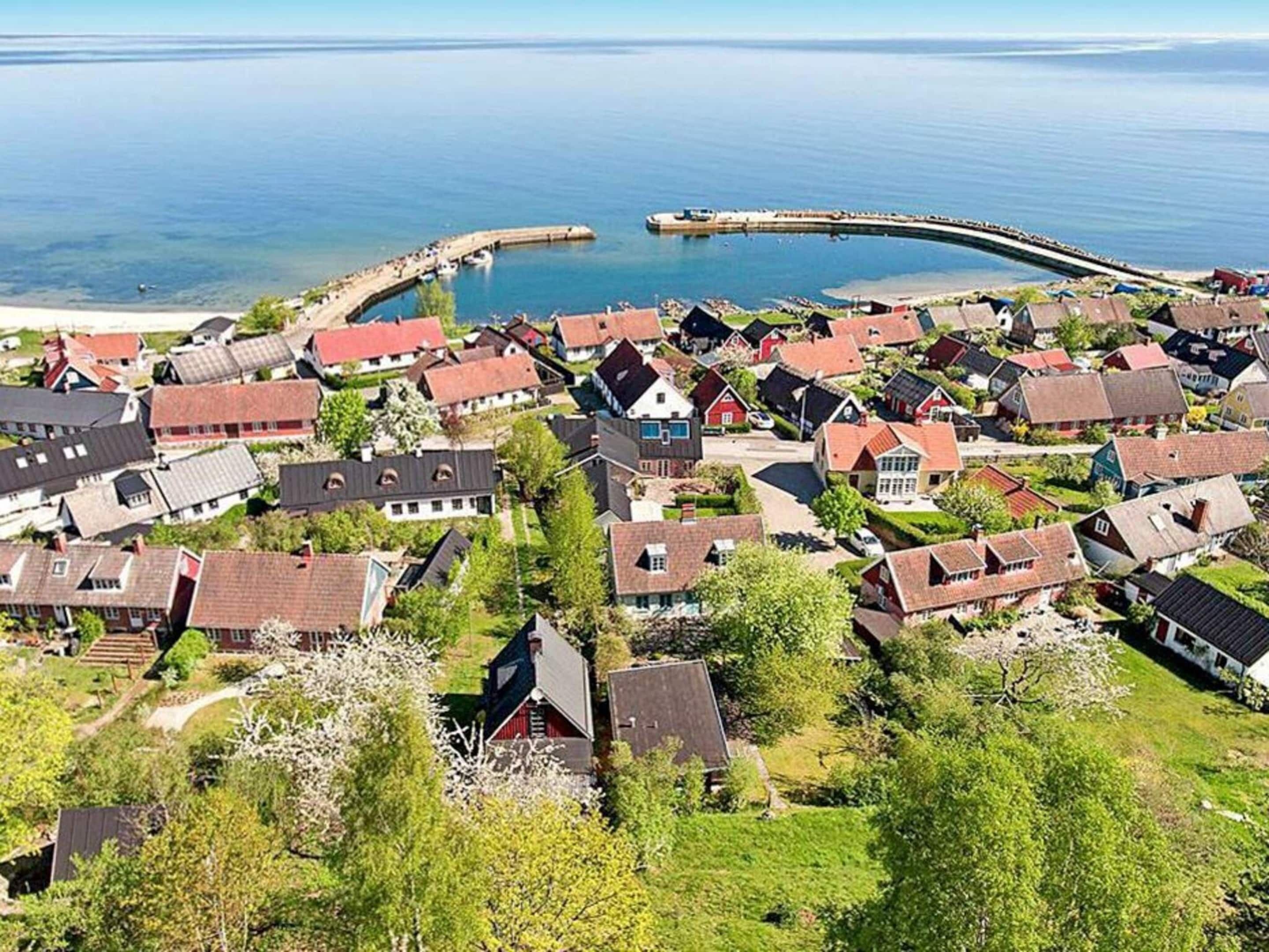 Uma vila costeira com casas tradicionais, um cais e uma praia.