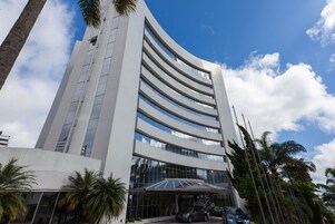 Um edifício moderno com fachada curva, janelas amplas e área de entrada coberta.