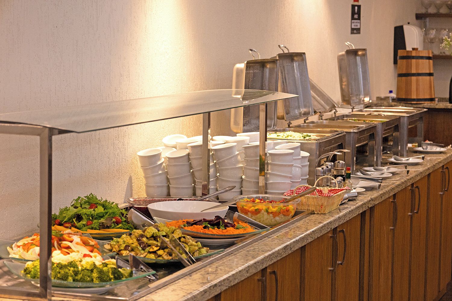 Buffet com diversos alimentos e utensílios de servir.