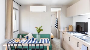 Cozinha compacta com fogão, pia e área de refeições com mesa e cadeiras.