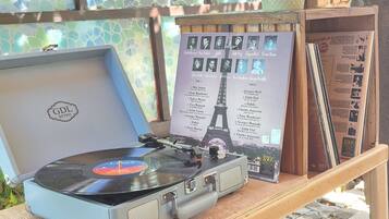 Um toca-discos sobre uma mesa de madeira com um cartaz da Torre Eiffel e uma planta.