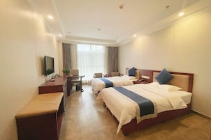 Quarto de hotel com duas camas, uma escrivaninha, uma cadeira e uma televisão.