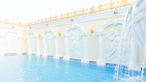 Piscina interna com colunas brancas ornamentadas e um corrimão decorativo.