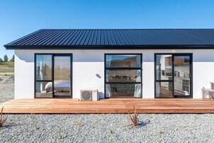 Uma casa moderna com telhado plano, amplas janelas de vidro e um deck de madeira.