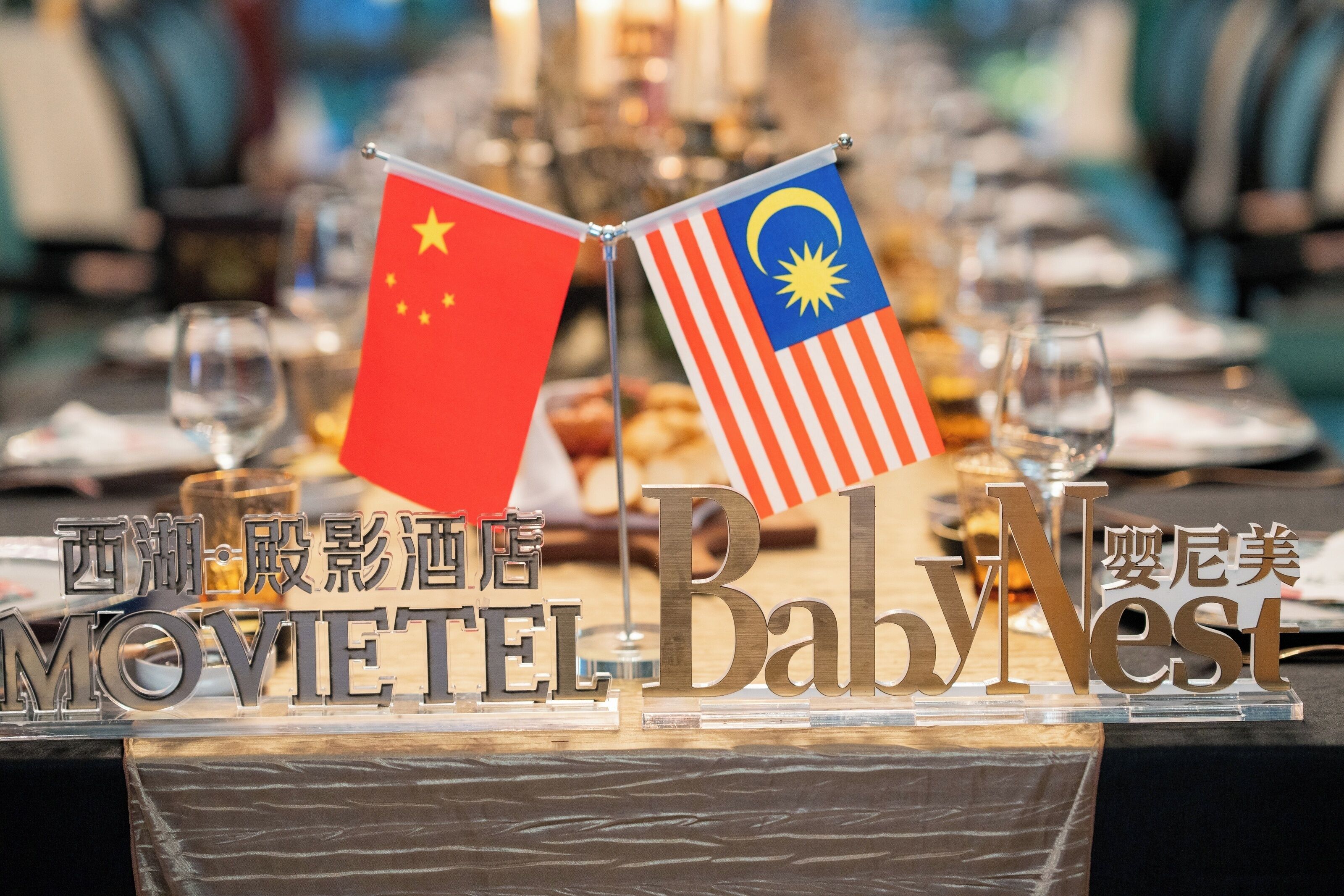 Um letreiro com bandeiras da China e da Malásia, e os textos 'MOVIETEL' e 'BabNesti'.