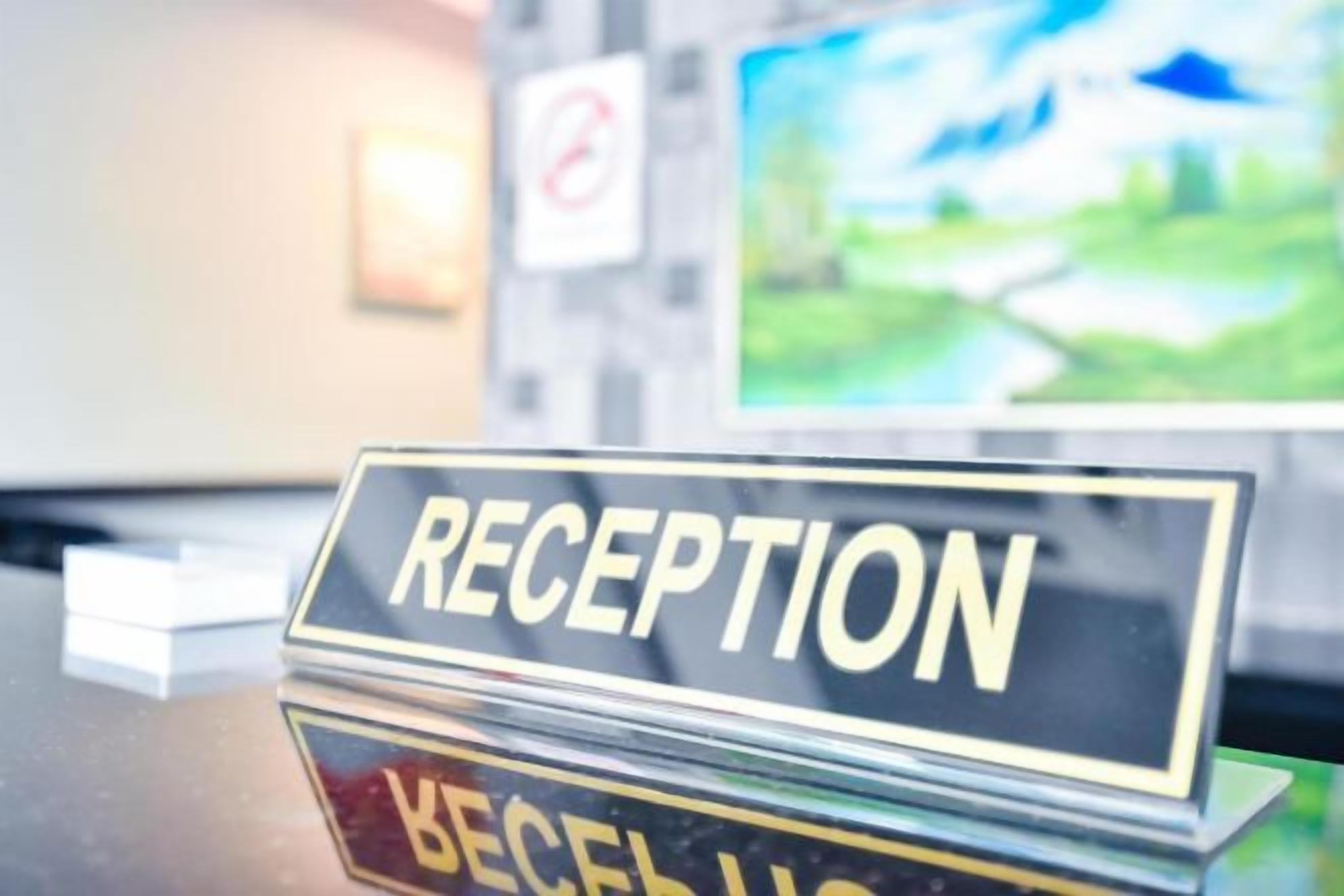 Bancada de recepção com uma placa identificando 'RECEPTION' e uma placa 'BEELU' abaixo.