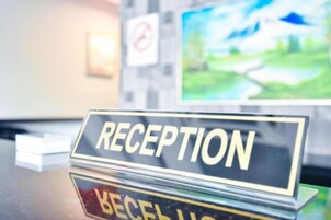 Bancada de recepção com uma placa identificando 'RECEPTION' e uma placa 'BEELU' abaixo.