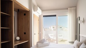 Quarto de hotel com uma cama grande, armário de madeira e varanda com vista para edifícios.