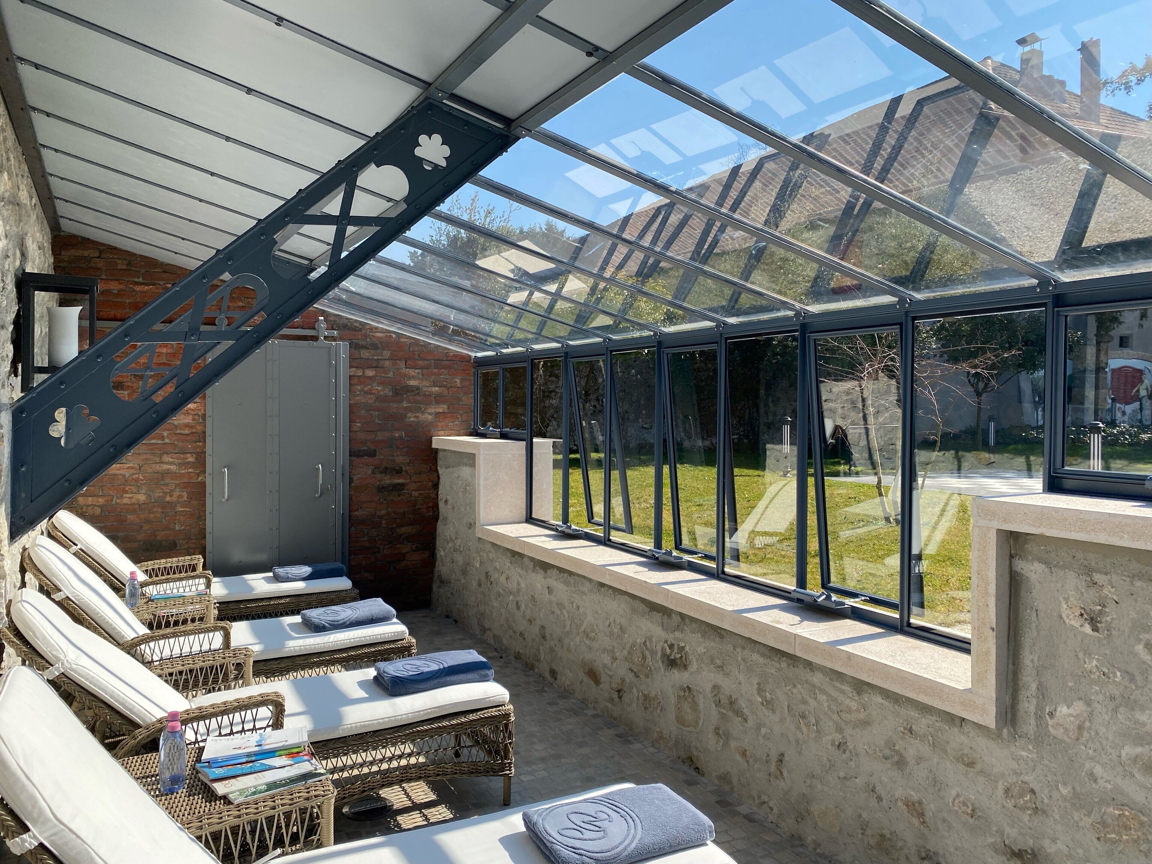 Uma sala de sol com móveis de vime, vista para o jardim e escada de metal.