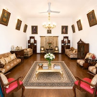Uma sala de estar tradicional com um candelabro, sofás, poltronas, uma mesa de centro e quadros nas paredes.