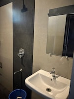Uma casa de banho com uma pia branca, um espelho e um chuveiro.