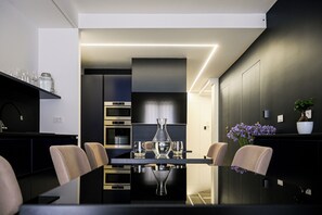 Uma zona de refeições moderna com mesa de vidro, cadeiras e um vaso de flores.