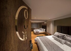 Um quarto moderno com duas camas, um espelho grande e uma parede de destaque em madeira.