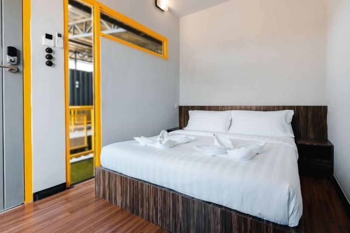 Quarto de hotel com cama, porta e vista para área externa.