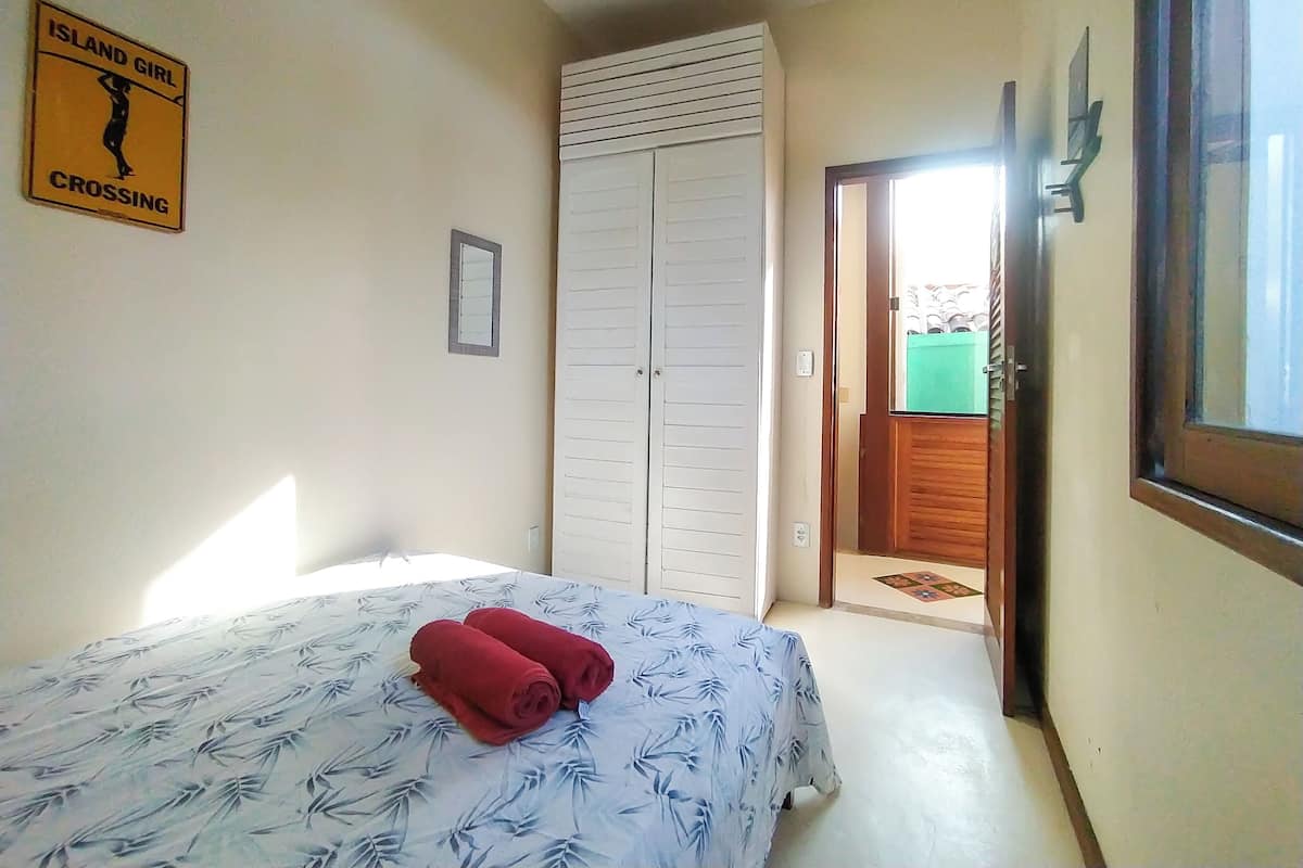 Quarto com cama, guarda-roupa, espelho e um aviso indicando passagem de uma nativa da ilha.