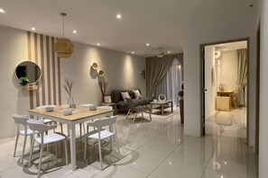 Uma sala de estar moderna com uma mesa de jantar, cadeiras brancas, um sofá e uma televisão.