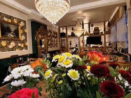 Um quarto com um lustre grande, um quadro na parede e uma mesa com flores.