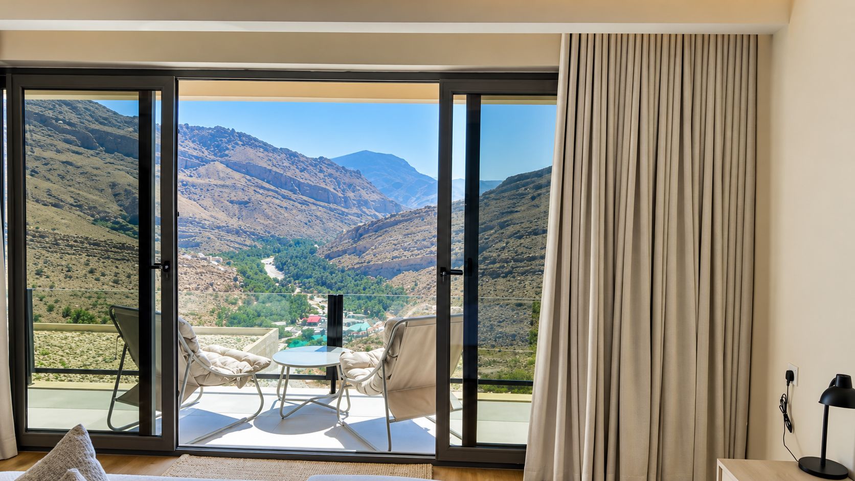Quarto com uma grande porta de correr de vidro que dá para uma varanda com vista para as montanhas.