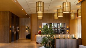 Um lobby moderno com área de bar, painéis de madeira e assentos.