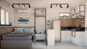 Quarto compacto com cama, mesas de cabeceira e armário embutido. Uma cozinha compacta com fogão e pia fica adjacente ao quarto.