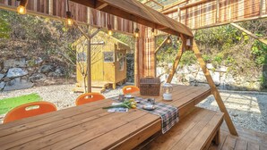 Um deck de madeira com uma mesa de piquenique, bancos e uma cesta de vime.