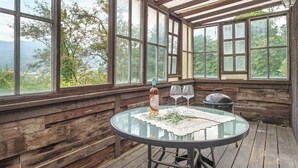 Um quarto com painéis de madeira, uma mesa de vidro, duas taças de vinho e uma garrafa de vinho.