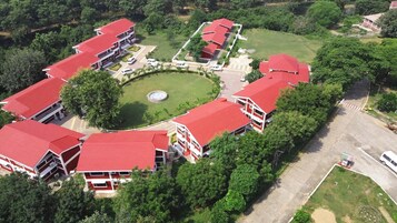 Vista aérea de um campus com vários edifícios com telhados vermelhos, cercado por áreas verdes e um pátio circular central.
