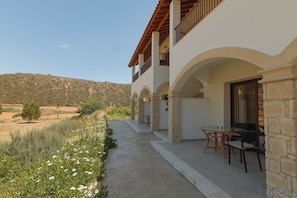 Um edifício com fachada de pedra, v árias arcos e uma varanda com mesa e cadeiras.