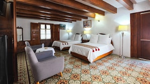 Quarto de hotel com duas camas, um sofá, uma televisão e um chão estampado.