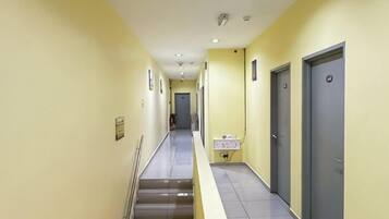 Um corredor com escadas, portas e um interruptor de luz na parede.
