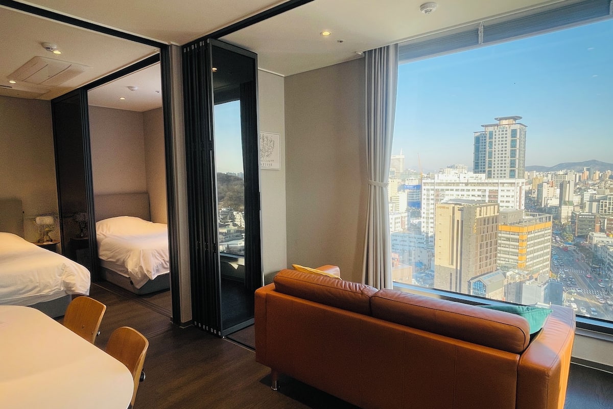 Quarto de hotel com vista para a cidade, um sofá, uma cama e uma mesa de jantar.