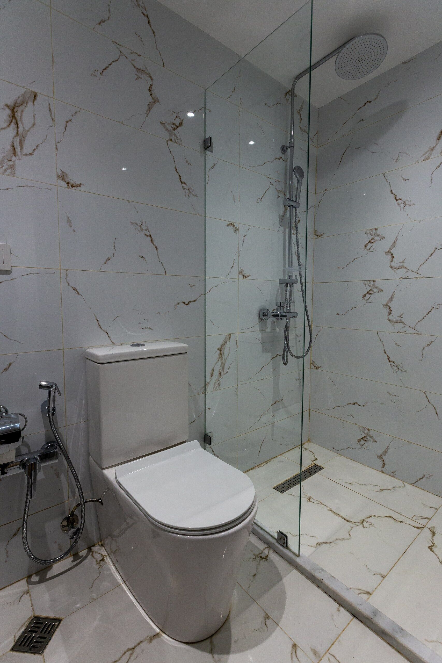 Casa de banho com cabine de duche em vidro, sanita e lavatório.