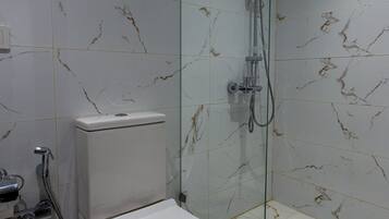 Casa de banho com cabine de duche em vidro, sanita e lavatório.
