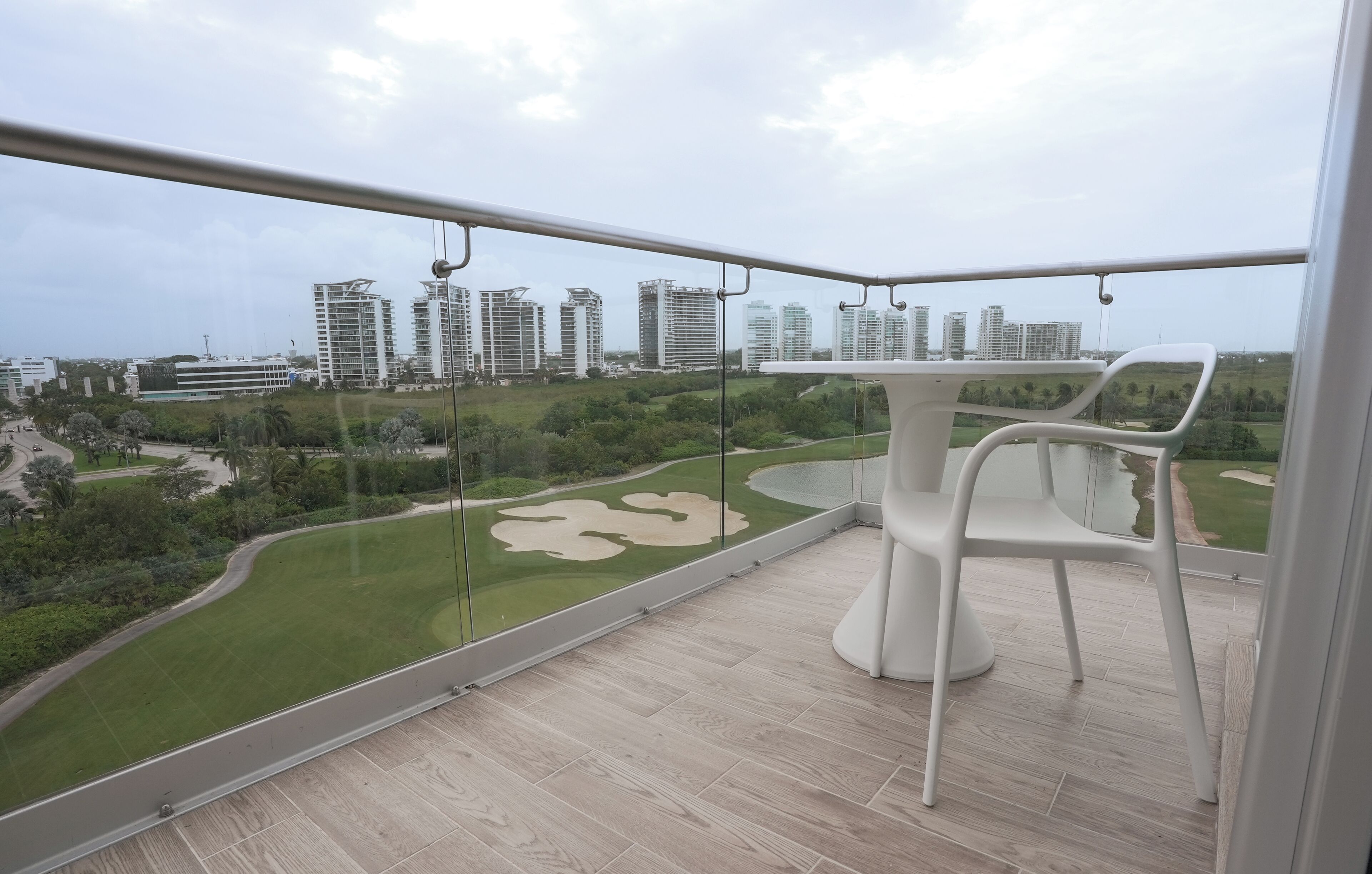 Uma varanda com vista para um campo de golfe e edifícios da cidade.