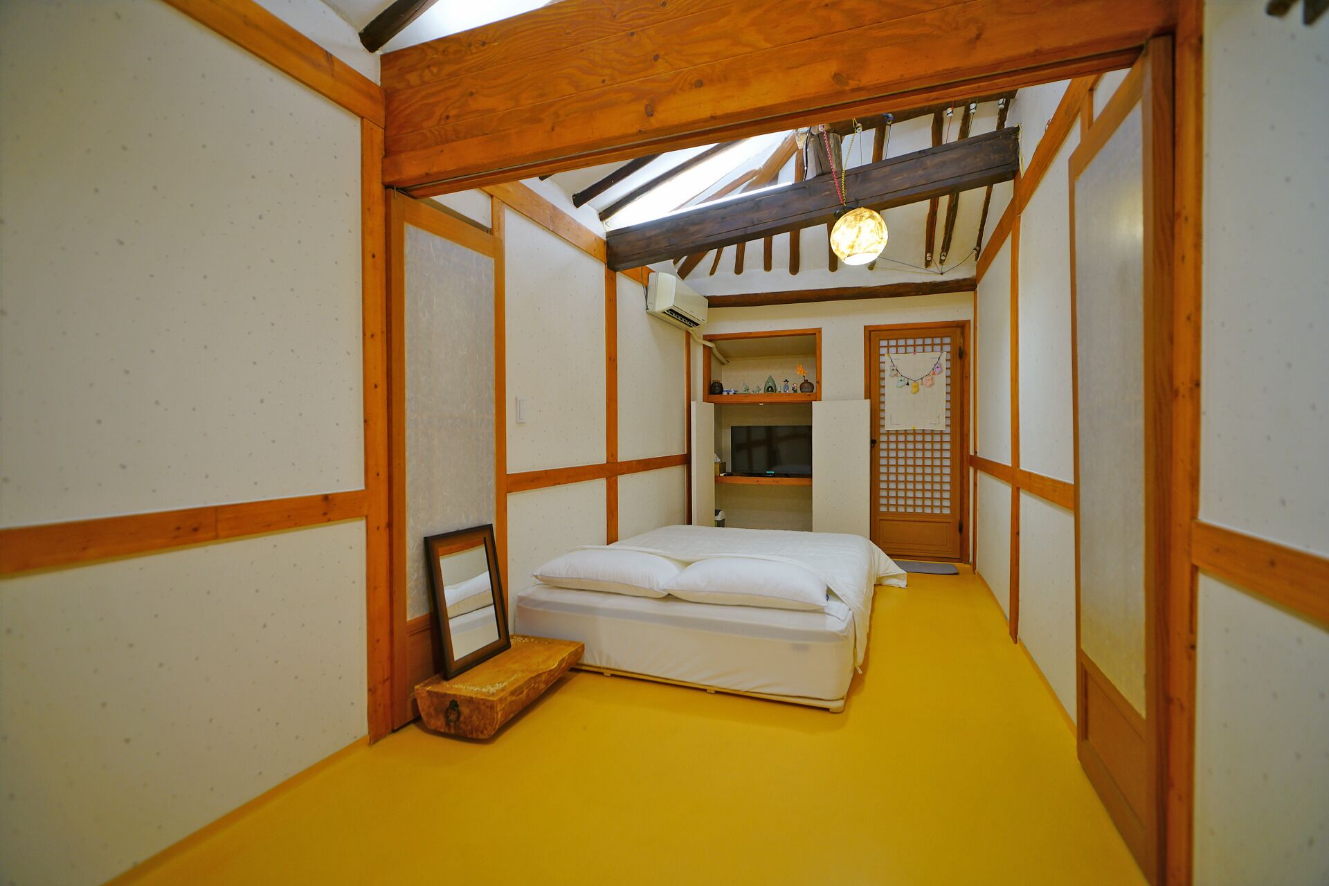 Um quarto tradicional japonês com piso de tatame, futon, estante de madeira com objetos decorativos e porta deslizante com decoração em papel.