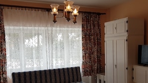 Um quarto com sofá, televisão e armário.