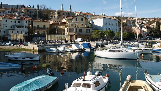 Uma marina com vários barcos atracados, cercada por edifícios com arquitetura tradicional.