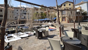 Marina com barcos atracados, área de estar ao ar livre e edifícios ao fundo.