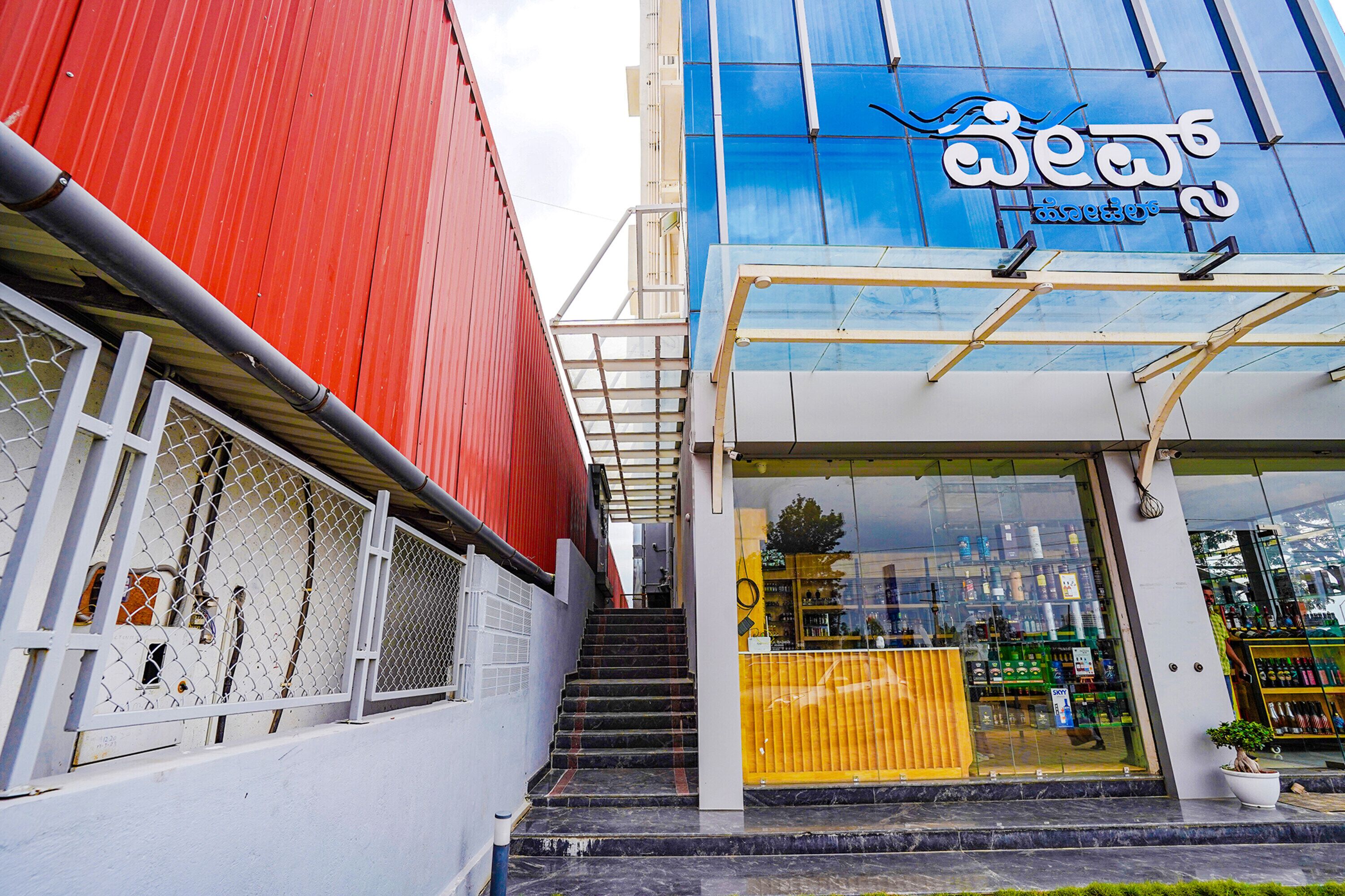 Um edifício com fachada vermelha, entrada de vidro e escadaria que leva à entrada.