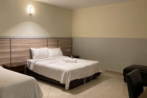 Quarto de hotel com cama, mesas de cabeceira e uma cadeira.